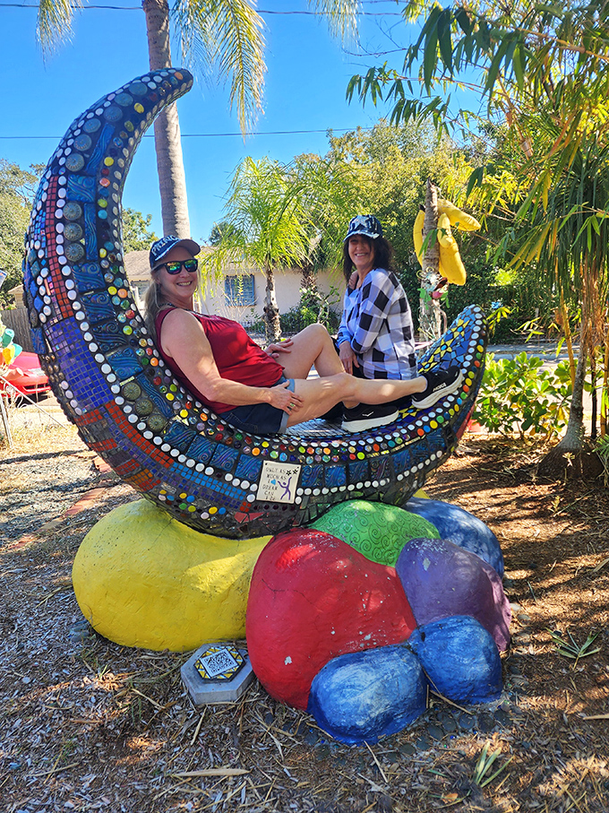 Two visitors enjoy the moon-shaped lounger, a perfect photo opportunity that's become a signature spot in this artistic wonderland.