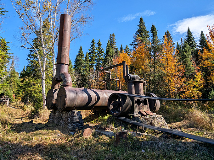 An old steam engine rests peacefully in the Allagash Wilderness Waterway, surrounded by vibrant fall colors and Maine&rsquo;s stunning natural beauty.