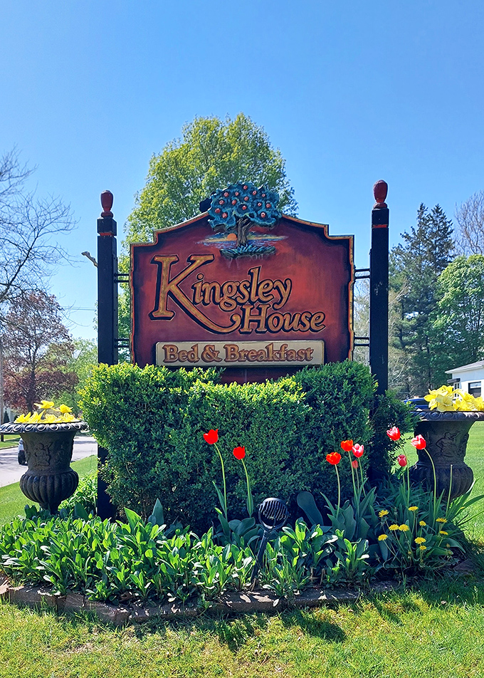 The Kingsley House sign stands amid spring blooms, a colorful herald welcoming travelers to this Victorian time capsule in Fennville.