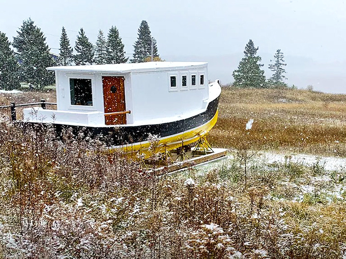 Winter wonderland meets maritime magic when snow blankets this yellow-hulled haven against Maine's dramatic coastal backdrop.