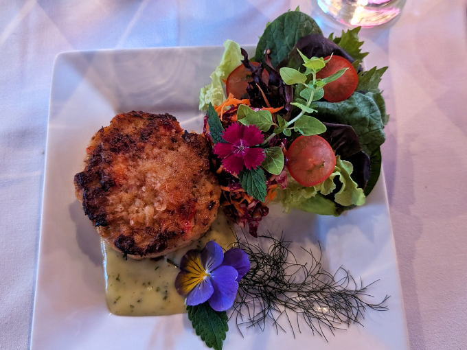 This isn't just any crab cake &ndash; it's a golden-brown disc of sweet crab meat, served with a garden-fresh salad brightened with edible flowers.