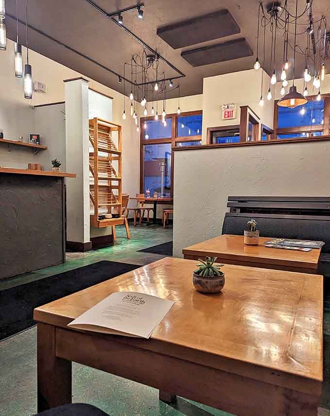 Modern lighting fixtures cast a gentle glow over wooden tables in this thoughtfully designed space where rustic meets refined without a hint of pretension.