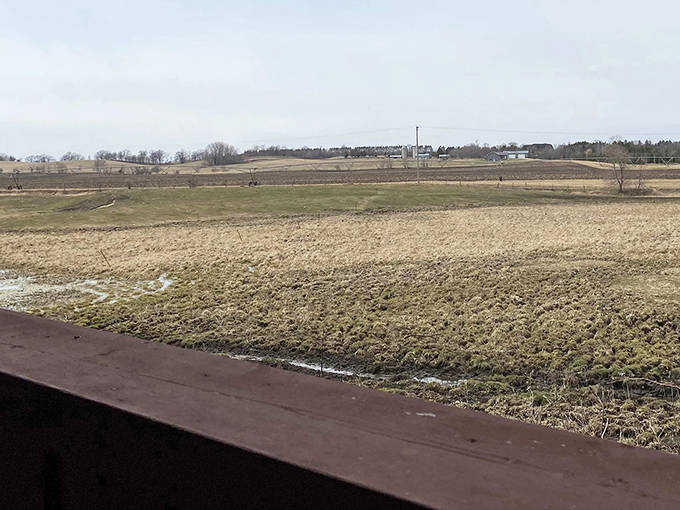 Beyond the bridge, Minnesota's pastoral beauty unfolds like a living landscape painting, complete with gently rolling fields.