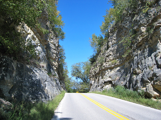 Nature and human engineering achieve an uneasy truce in this dramatic roadcut, where vegetation slowly reclaims the upper reaches.