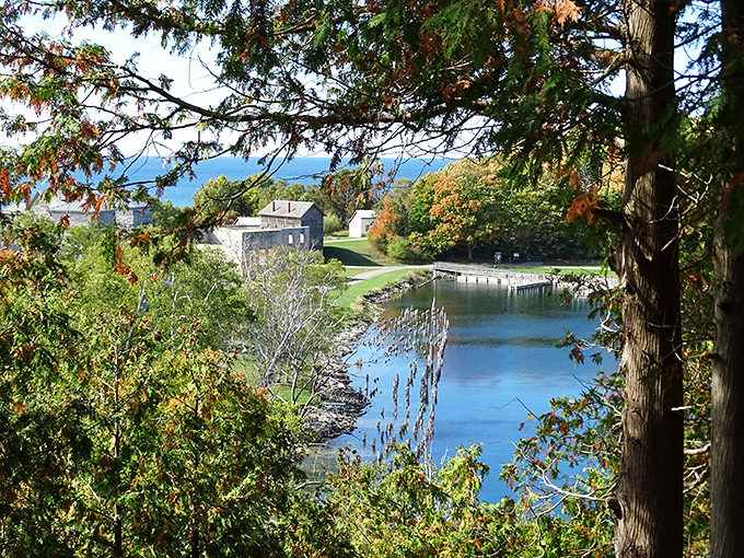 Autumn colors frame the peaceful harbor where industrial ships once docked, the water reflecting centuries of change in this historic landscape.
