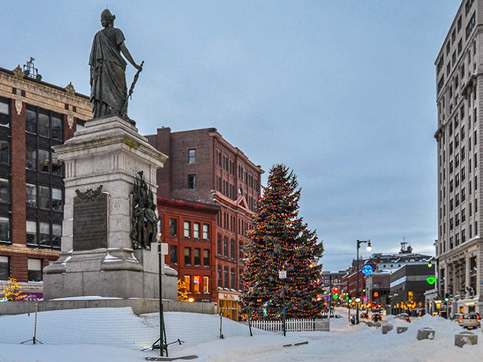 Portland's Monument Square during the holiday season, featuring a towering Christmas tree and historic statue dusted with snow.
