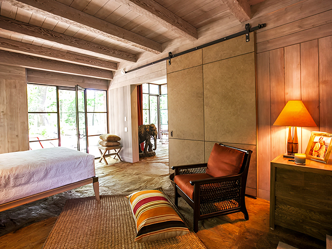 Sliding barn doors and exposed beams bring rustic charm to this bedroom, while luxurious linens promise restful slumber.