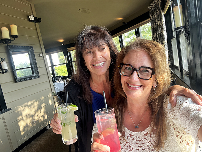 Happy diners raising colorful cocktails in a sun-dappled corner &ndash; the joy of good company enhanced by exceptional drinks.