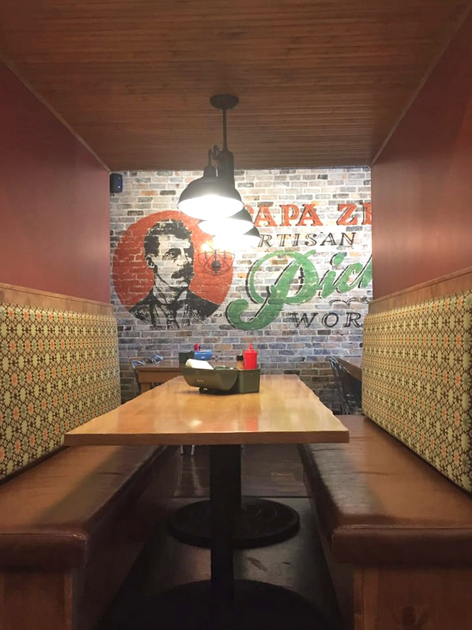 Cozy booth seating against the signature brick wall creates an intimate dining experience in this pickle-themed wonderland.
