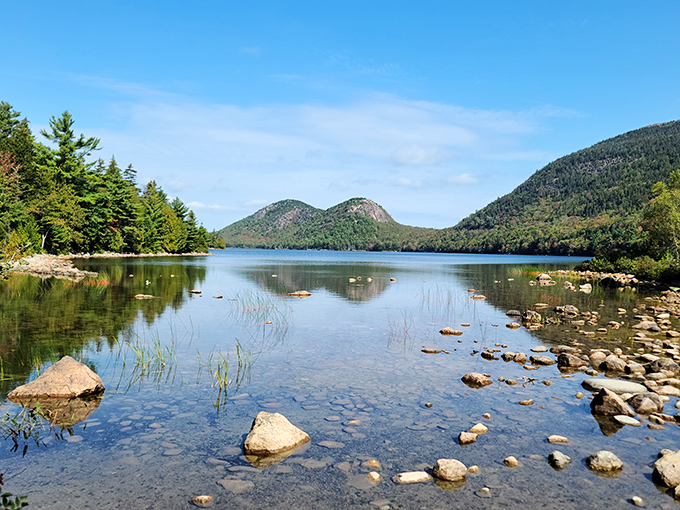 Crystal clear lake reflecting the surrounding mountains &ndash; nature's mirror showing off Maine's pristine wilderness beauty.