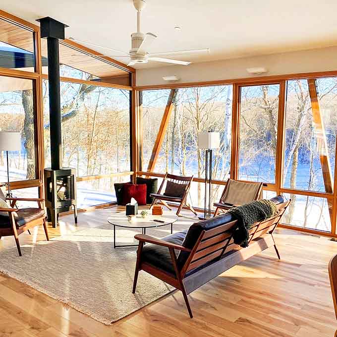 The living room's mid-century modern furniture and wall of windows create a space where you can't decide whether to admire the interior design or the exterior landscape, so you just admire both.