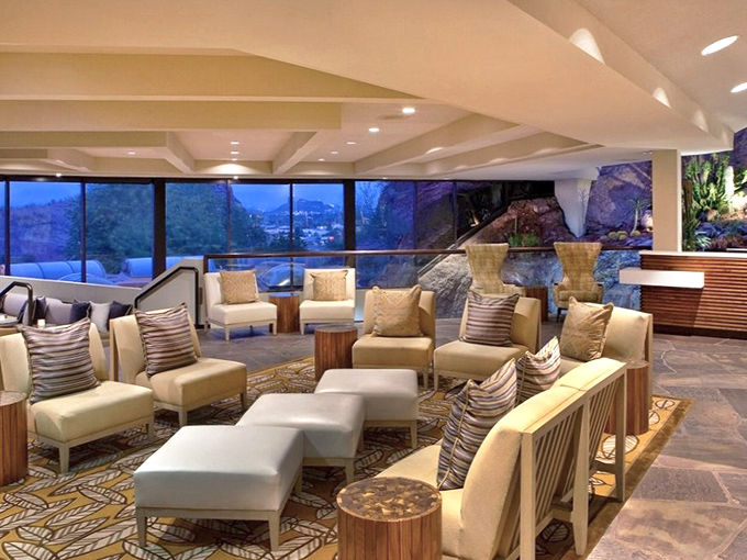 Elegant lounge seating invites conversation against floor-to-ceiling windows framing the dramatic Sonoran landscape beyond.