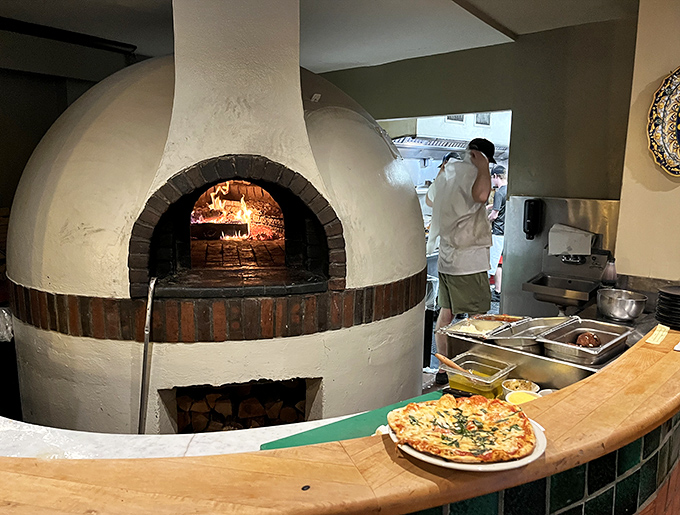 The wood-fired oven isn't just equipment; it's the restaurant's fiery heart, imparting that irreplaceable smoky kiss to everything it touches.