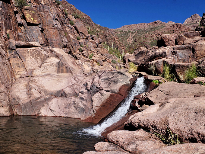 Desert waterfall creates a natural water slide over smooth red rocks, proving Mother Nature designs the best amusement parks.