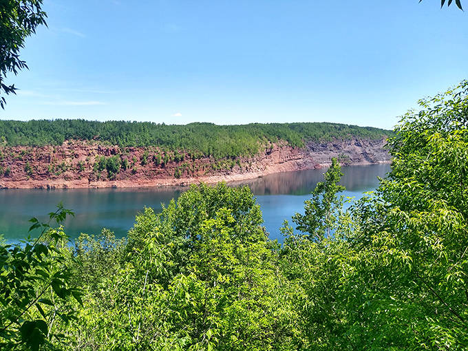The Rouchleau Mine Pit's dramatic red walls and turquoise waters transform industrial history into breathtaking natural wonder.