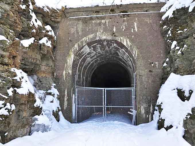 Winter transforms the tunnel into a snow-framed portal, temporarily closed yet hauntingly beautiful in its seasonal slumber.