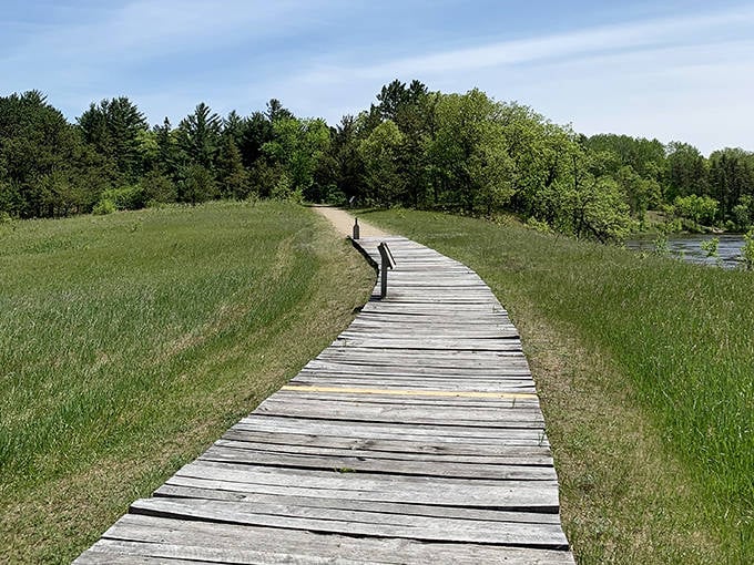 This weathered boardwalk stretches across the prairie like a wooden welcome mat rolled out by Mother Nature herself.