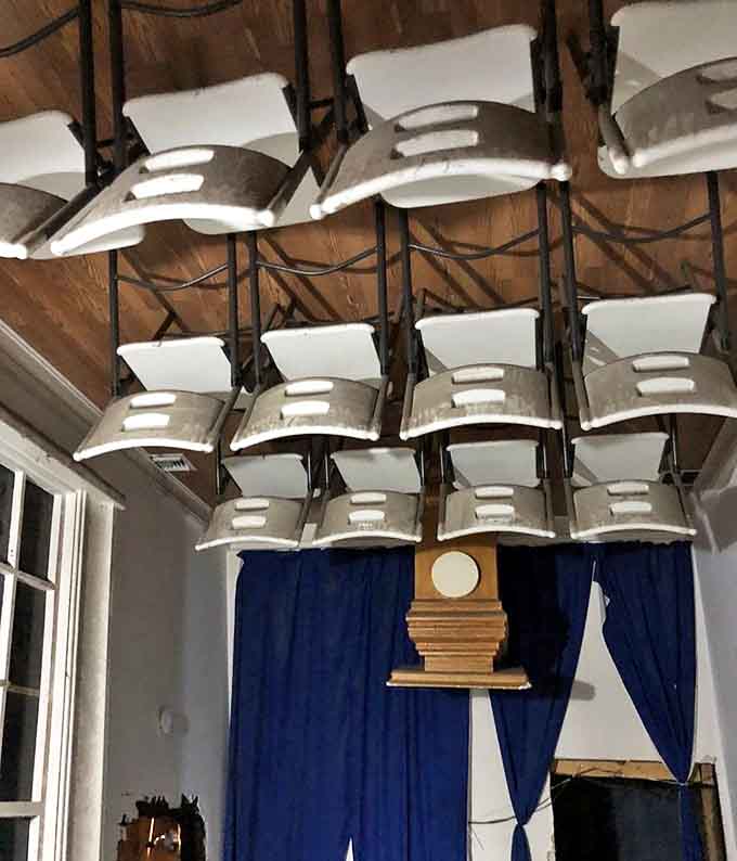 Reporters would struggle to take notes in this upside-down press room, where gravity-defying chairs hang from what should be the floor.