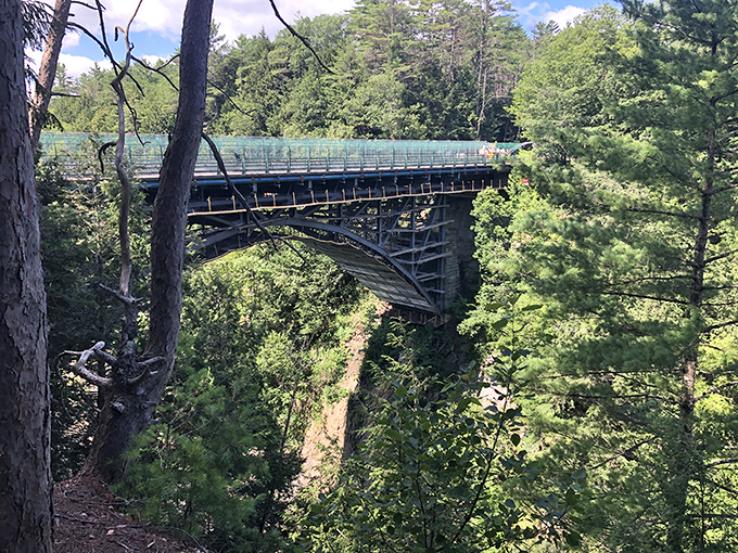 The view stretches for miles beyond the gorge, with Vermont's rolling hills creating layers of green that fade into the distant horizon.