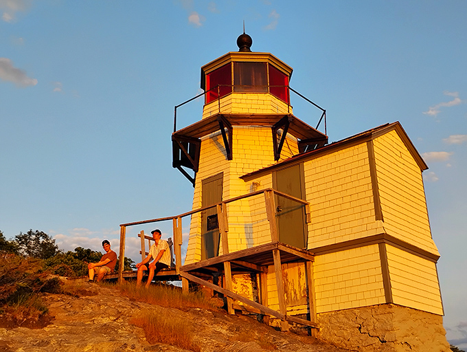 Sunset visitors bask in golden hour magic, the lighthouse's deck offering front-row seats to nature's daily farewell performance.
