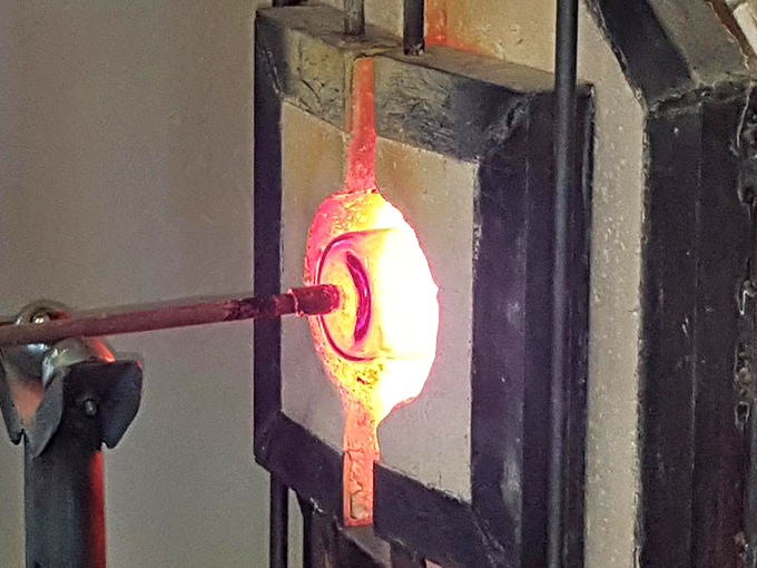 The furnace's fierce glow illuminates the workshop, a modern echo of fires that have transformed sand into art for millennia.