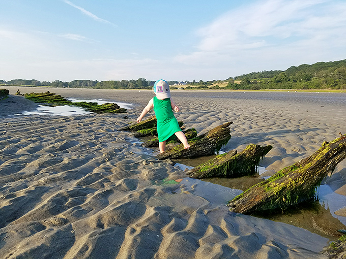 Young adventurer tests wooden remnants, connecting with history through touch rather than textbooks.