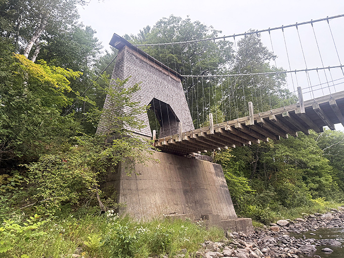 The bridge's distinctive tower rises from the riverbank, its weathered shingles telling tales of countless Maine seasons. 