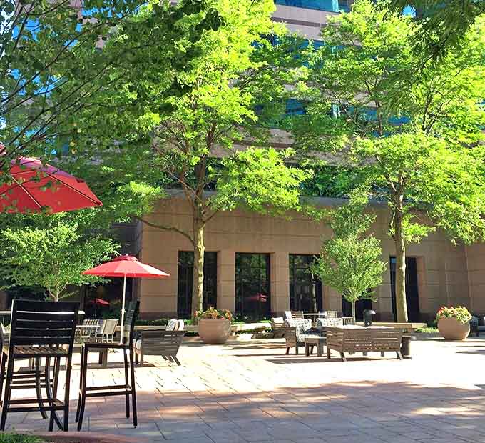 Outdoor seating creates urban oasis moments &ndash; red umbrellas pop against greenery, offering fresh-air retreats between indoor indulgences.