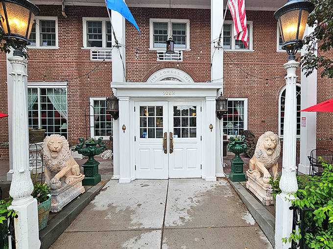Stone lions stand guard at the entrance, silently witnessing arrivals and departures while white columns frame doorways that have welcomed guests for generations.
