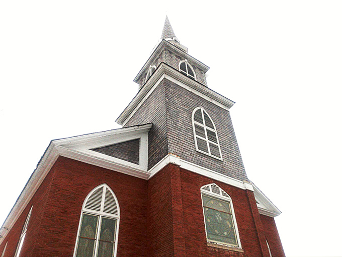This church steeple reaches skyward like architectural poetry, its weathered shingles telling stories of countless Vermont seasons.