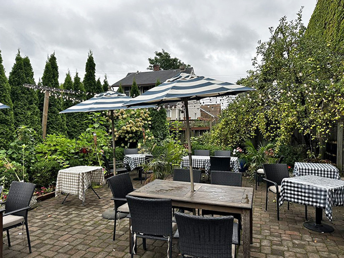 The outdoor patio offers a garden oasis in warmer months, where checkered tablecloths and umbrellas create the perfect setting for summer dining.