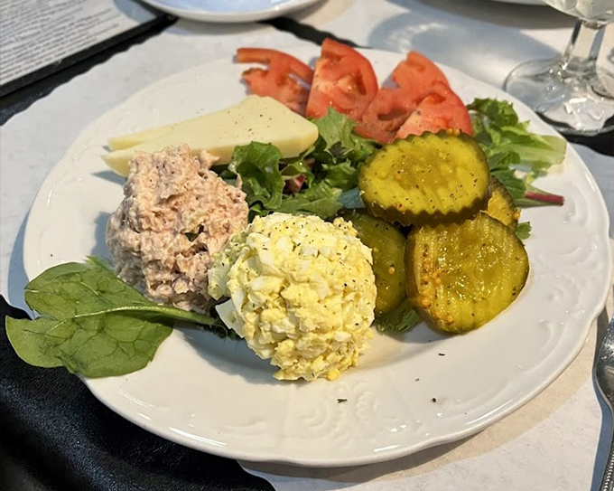 A plate that celebrates simplicity &ndash; egg salad, tuna salad, fresh tomatoes and pickles arranged with the care usually reserved for fine art.