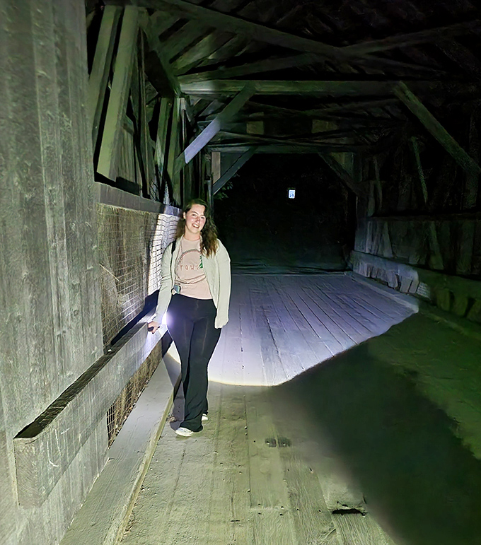 A flashlight beam cuts through darkness inside the bridge, where some visitors report feeling unseen fingers brush against them.