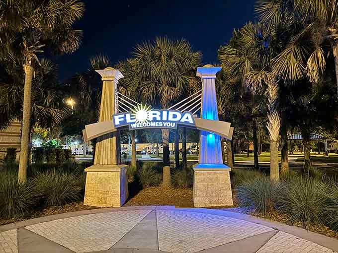 Night transforms the welcome sign into something magical, its lit columns standing guard over travelers' dreams of sunshine and adventure ahead.