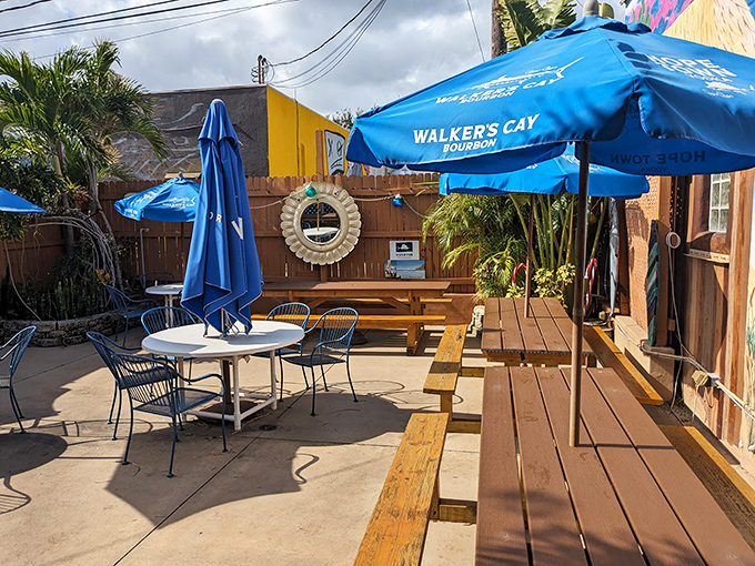 Wooden benches under blue umbrellas create the perfect outdoor dining space where Florida breezes carry the scent of salt and fried goodness.