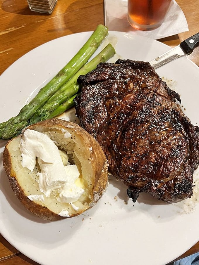 A ribeye with the kind of char that meat-lovers dream about, accompanied by a loaded baked potato that's a meal in itself.