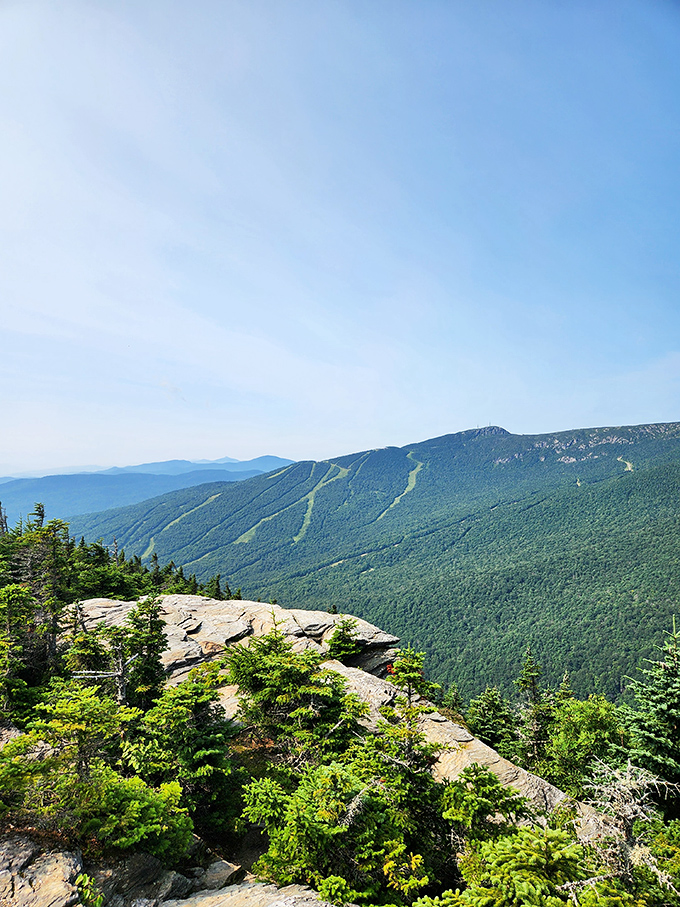 Standing on this rocky outcrop feels like being on top of Vermont's world, with mountains rolling away like frozen waves.