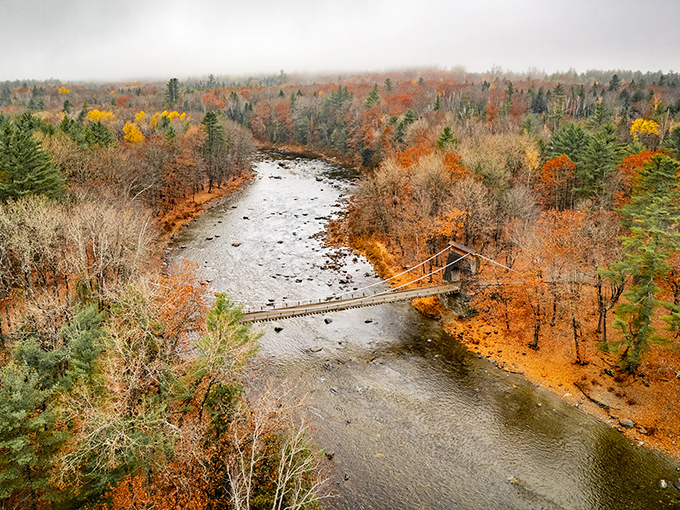 An aerial perspective reveals how perfectly the Wire Bridge complements its natural surroundings, nestled among Maine's forests and flowing waters.