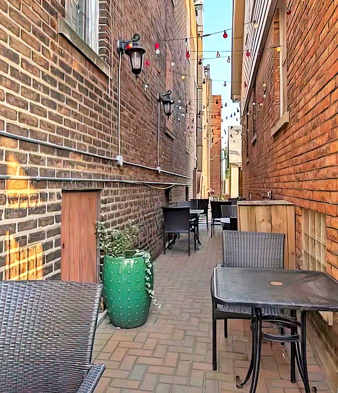 The narrow alleyway dining space transforms urban architecture into an intimate setting for memorable meals between brick walls.