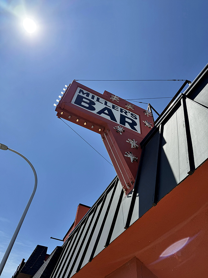 Looking up at the vintage Miller's Bar sign against a blue Michigan sky, a symbol of continuity in a world of constant change.