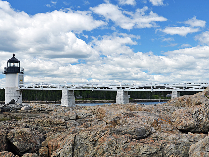 The view from the water showcases Port Clyde's perfect placement between forest and sea, with boats bobbing in the protected harbor.