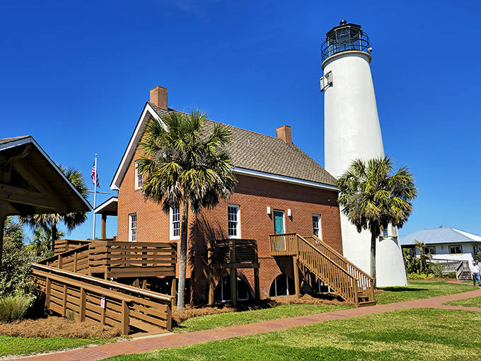 The Cape St. George Light stands proudly with its white tower rising from a charming brick keeper's house. Palm trees frame this postcard-perfect scene on St. George Island.