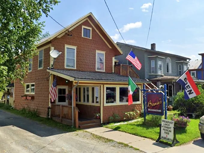 Bernie's Restaurant welcomes visitors with its charming brick exterior and colorful flags, standing like a culinary beacon in Montpelier's neighborhood landscape.