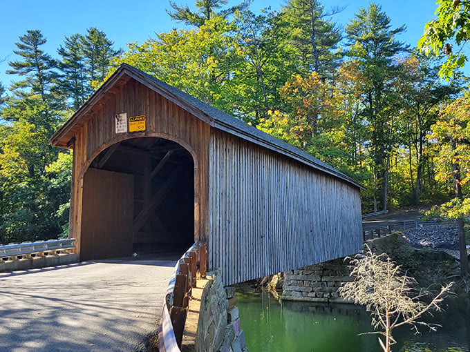 Babb's Bridge welcomes visitors with its classic wooden frame, standing proudly against a backdrop of vibrant autumn foliage.