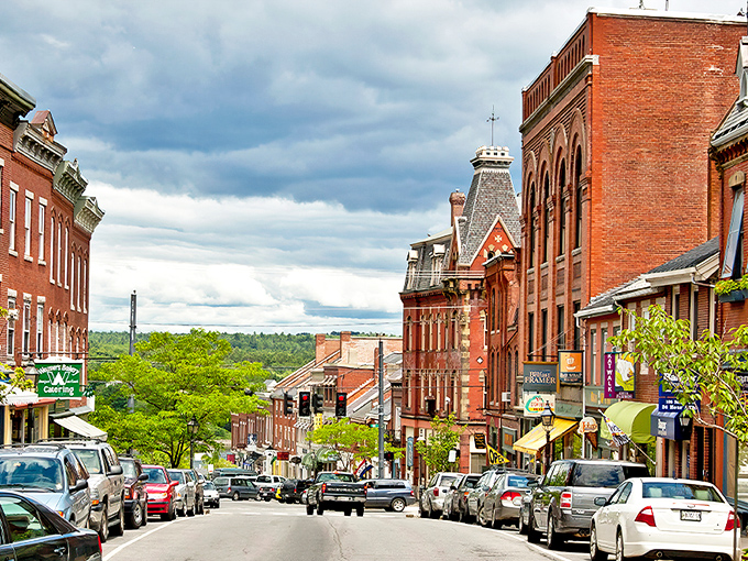 Belfast's charming Main Street showcases classic New England brick architecture against a backdrop of blue skies and distant hills.