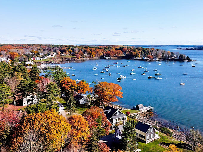 Kennebunkport's harbor glows with autumn colors, as boats rest peacefully in the blue waters beneath a canopy of fiery foliage.