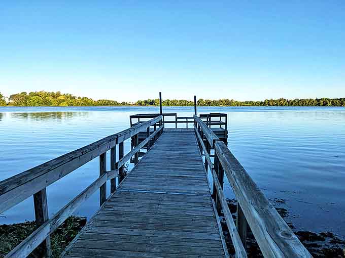 A wooden dock stretches into the mirror-like waters of Monson Lake, inviting visitors to pause and soak in the peaceful Minnesota landscape.