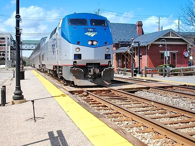 The sleek silver and blue Amtrak train pulls into the historic brick station, ready to whisk families away on affordable adventures through Florida's hidden gems.