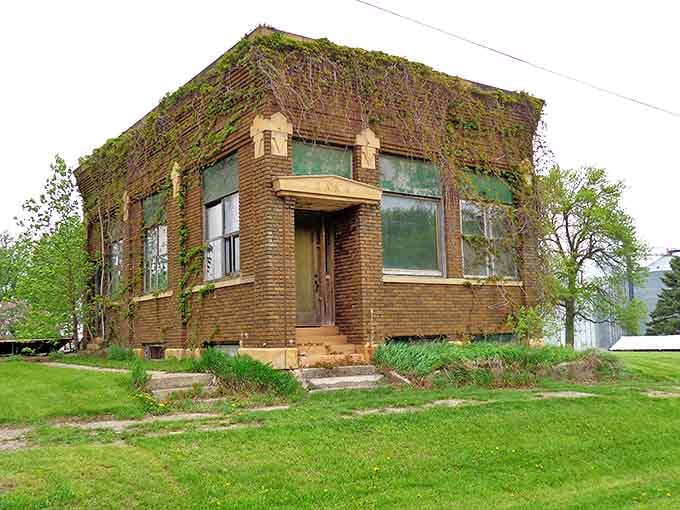 Seasons change, but this abandoned bank remains, its brick walls now wearing a lush green coat of vines instead of handling green cash.