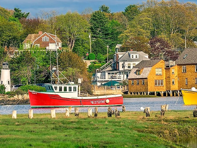 A classic red lobster boat rests at harbor with weathered wooden buildings standing sentinel along Kennebunkport's working waterfront.